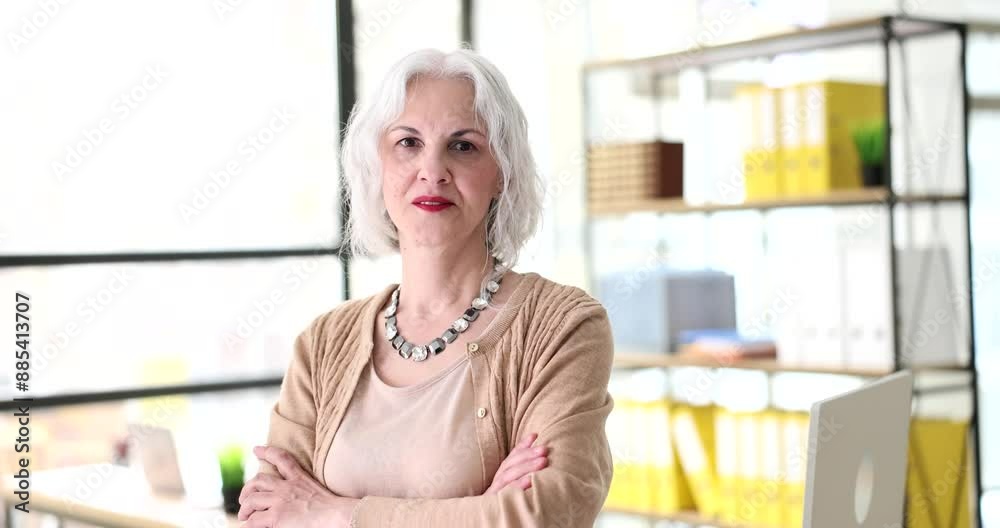 Serious grey haired businesswoman with crossed arms in company office ...