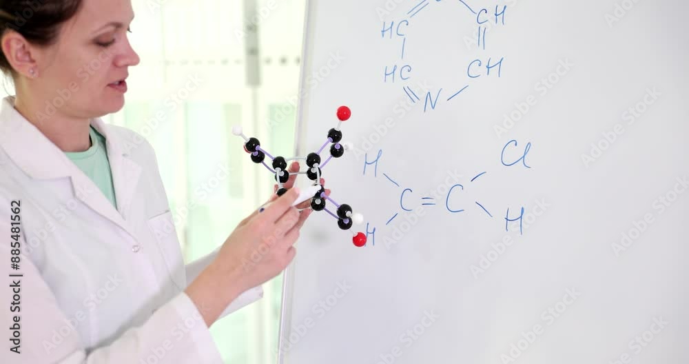 Serious woman examines molecules of chemical compounds holding model in ...