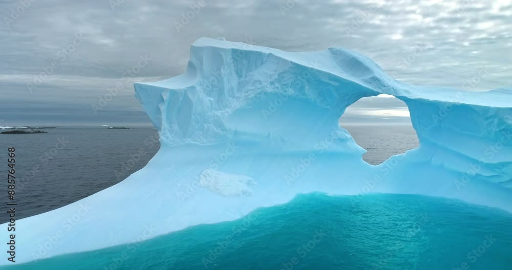 Huge blue towering iceberg with melted hole inside drifts polar ocean ...