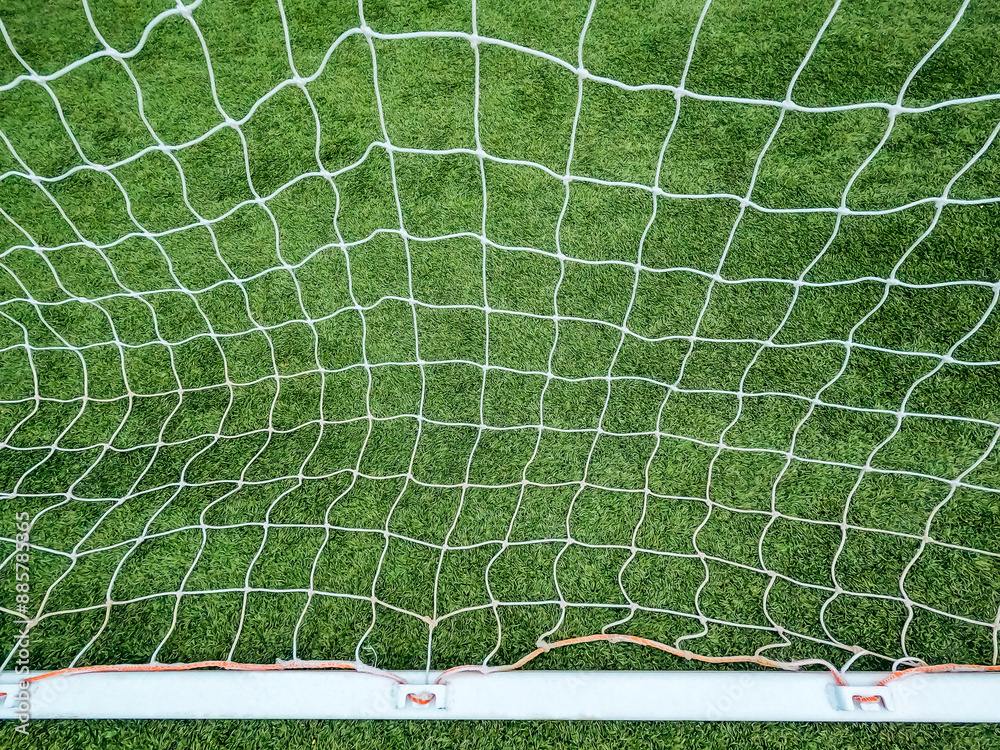 Soccer or football goal net backstop on a green turf field. Straight on ...