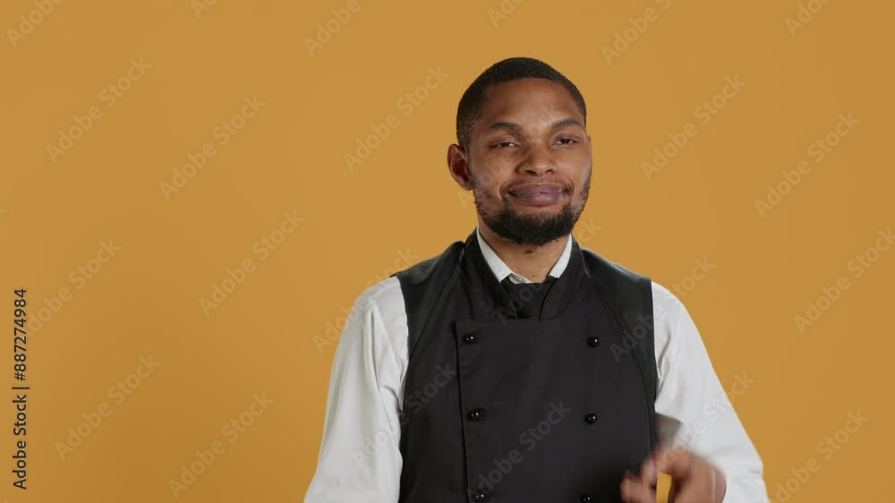 Skilled waiter showing a thumbs up symbol in front of the camera ...