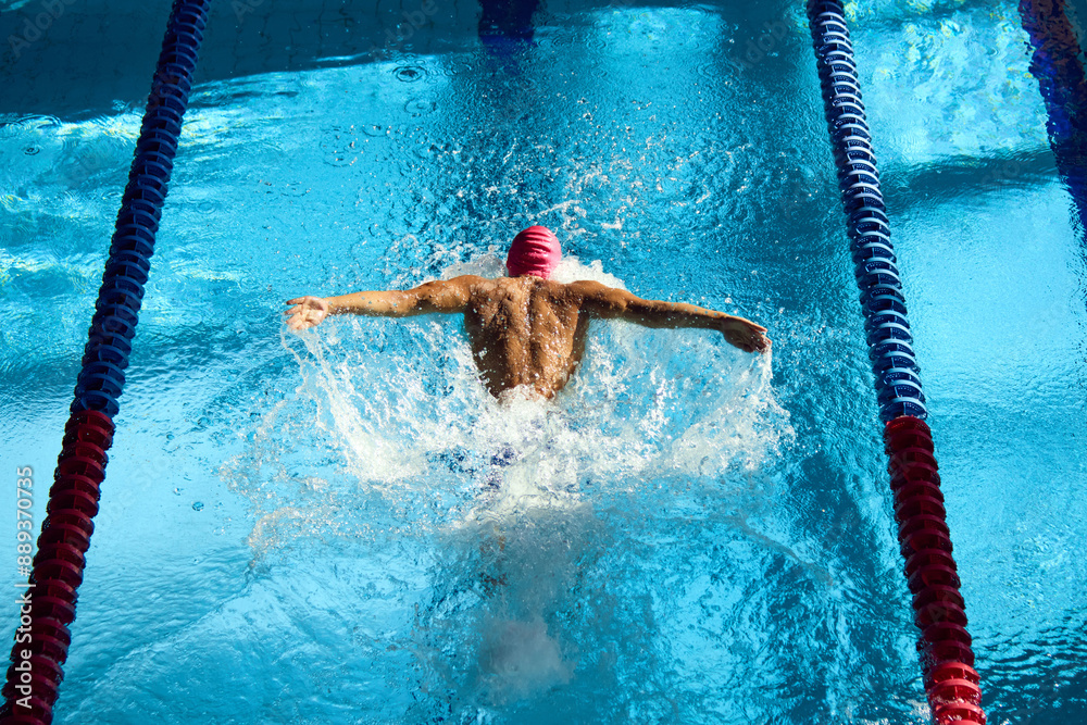 Swimmer, seen from above, powers through water with butterfly stroke ...