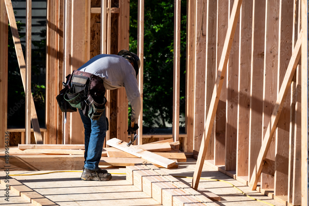 Construction worker in toolbelt and hard hat working with a hammer on ...