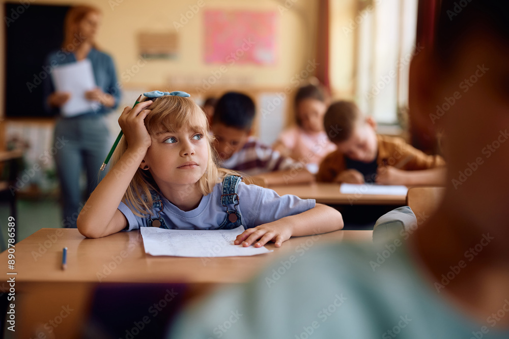 Little girl thinking while having test at elementary school classroom ...