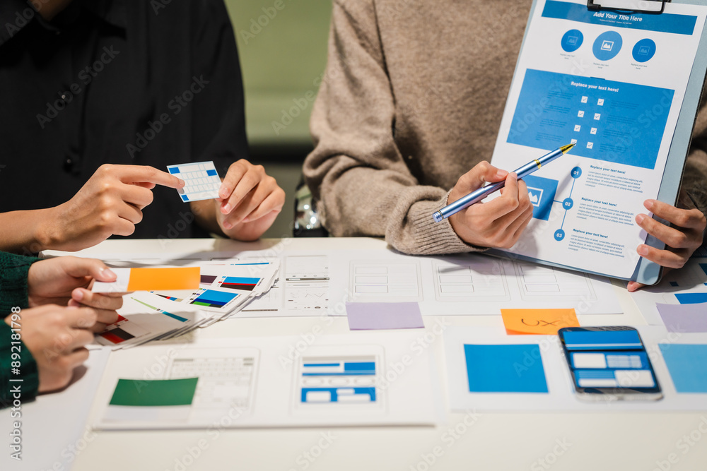 Close-up of hands working on UX/UI design at a desk. Papers with ...