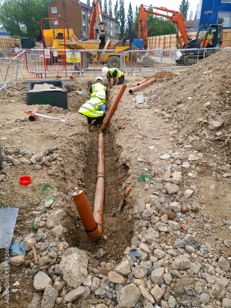 Construction workers installing underground drainage system with pipes ...