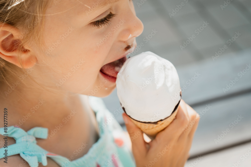 portrait blonde girl in park eating cold ice cream, ice cream melts and ...