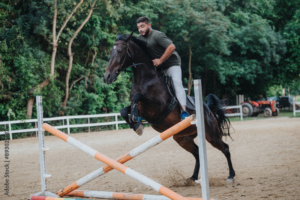 Man riding a horse while jumping over an obstacle during an equestrian ...