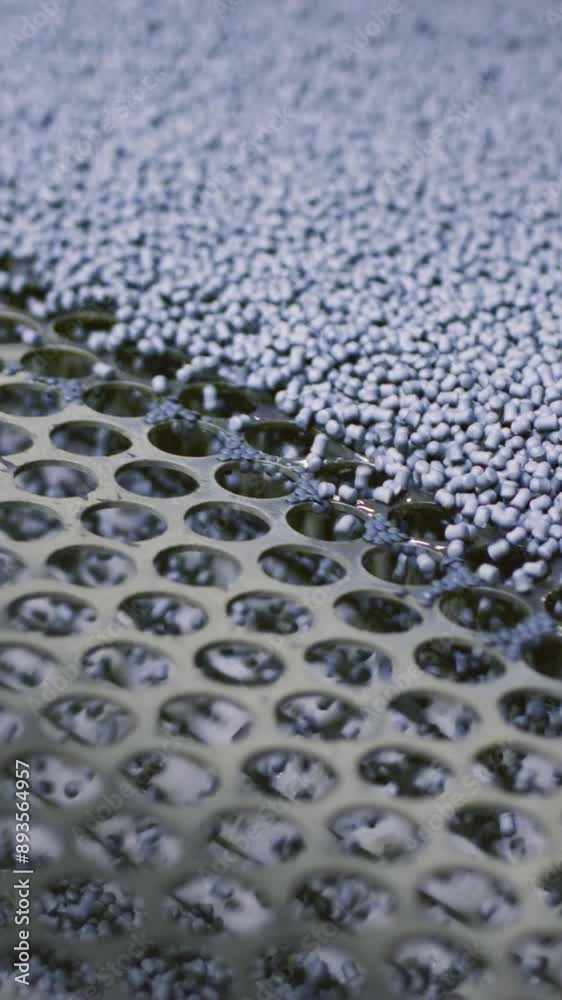 A waste recycling plant. Plastic granules move on a conveyor belt in ...