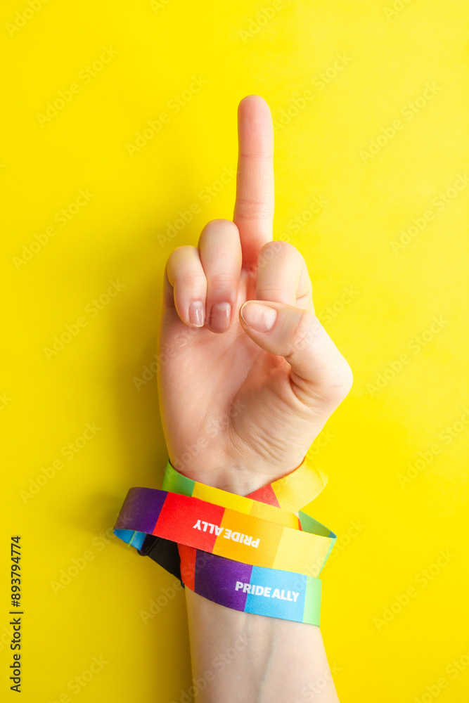 Women's hand wrapped in rainbow ribbon LGBT symbol shows off the middle ...