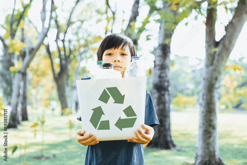 Cheerful young asian boy holding recycle symbol bin on daylight natural ...