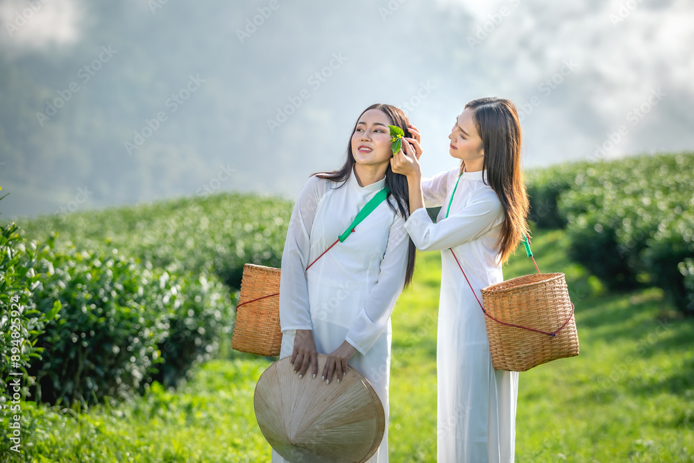 Smiling happy two beautiful Asian woman wearing traditional Vietnamese dresses holding baskets ...