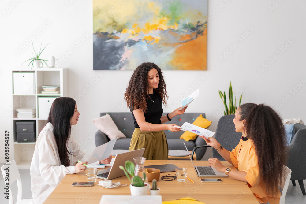 A group of three diverse women working together in a modern office ...
