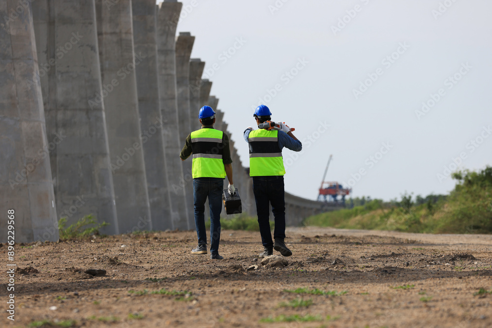 Two railway engineer carrying level survey cameras Walking with a ...