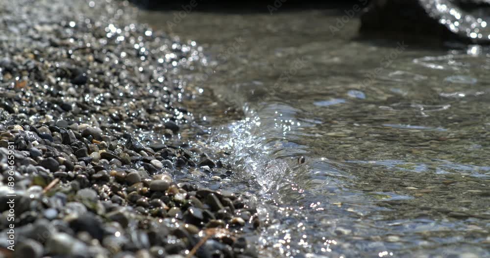 Pebble shoreline with sparkling water ripples in slow motion at 800 fps ...