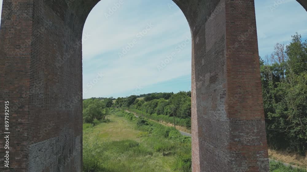 Drone passing through the arches of a viaduct bridge in the countryside ...