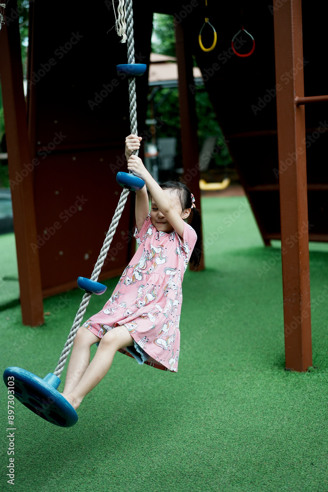 Adorable little girl sitting on zipline seat and smiling happily while ...