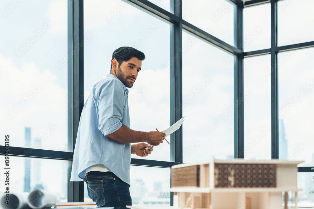Smart engineer walking around and holding blueprint or project plan ...