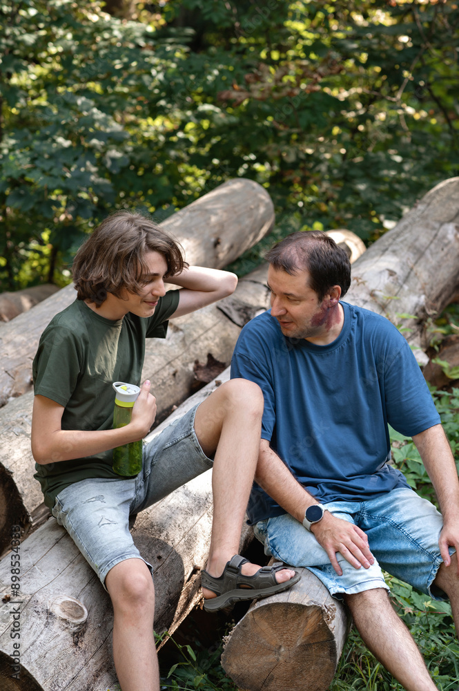 Foto de Father and his teenage son have a break while family hiking in ...