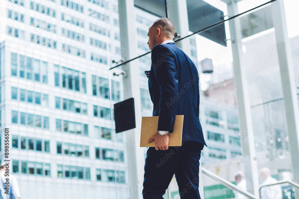 Back view of successful businessman dressed in elegant suit holding ...