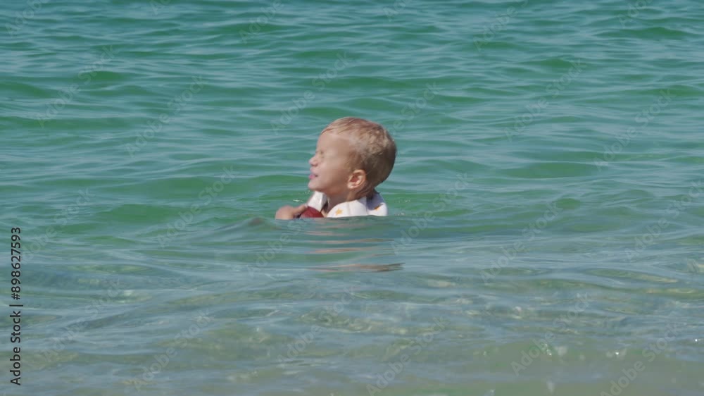Happy little boy in swim vest life jacket playing on summer beach ...