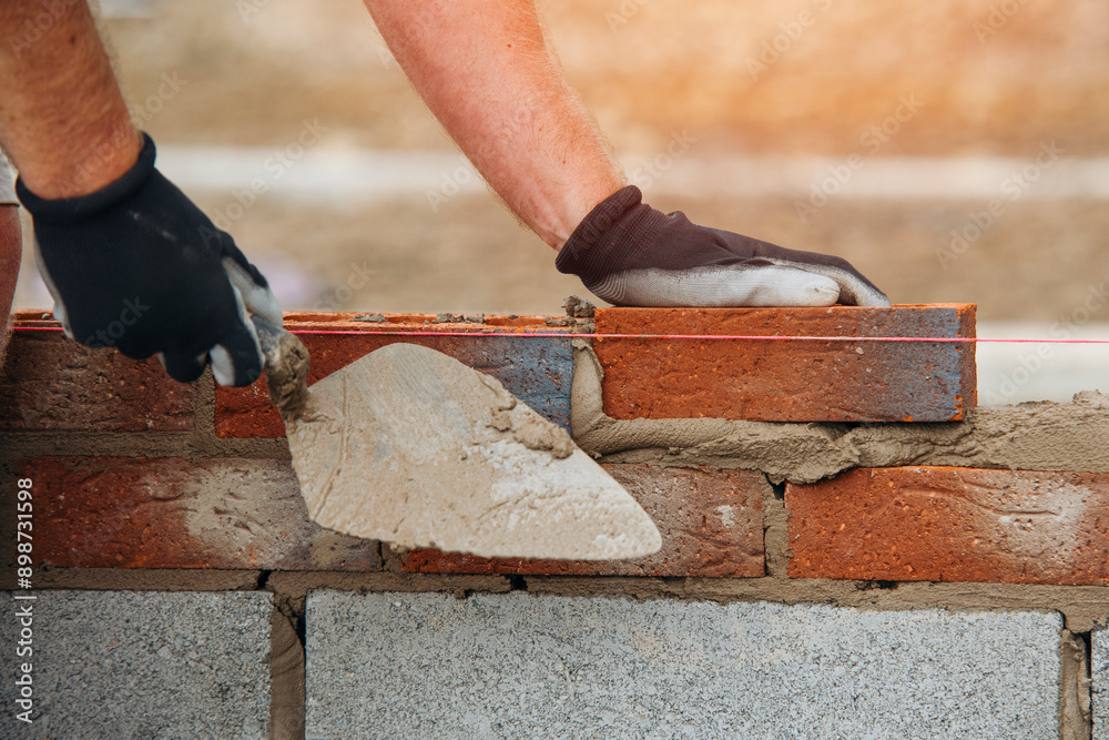Construction Worker Using Trowel to Spread Mortar Between Red Bricks ...