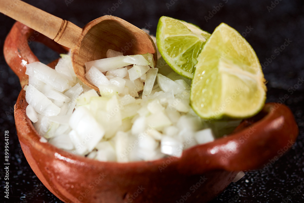 Diced onion and some sliced lemons, placed in a clay pot to serve with ...