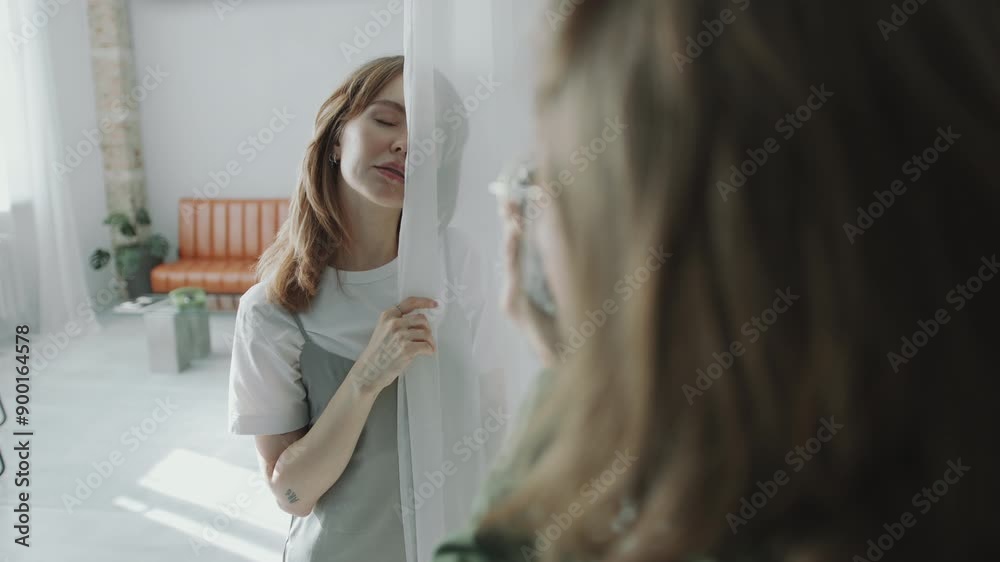 Young beautiful model posing behind white sheer curtain in front of ...
