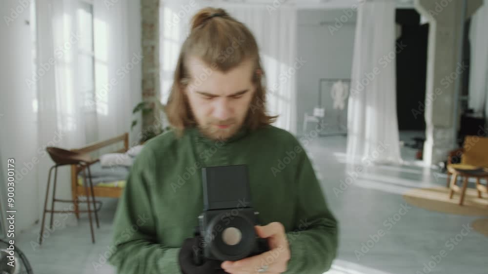 Male photographer with long hair and beard wearing glove looking at ...