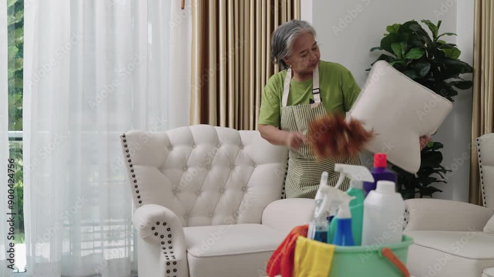 Handheld Shot Footage shows a housekeeper wearing an apron dusting and ...