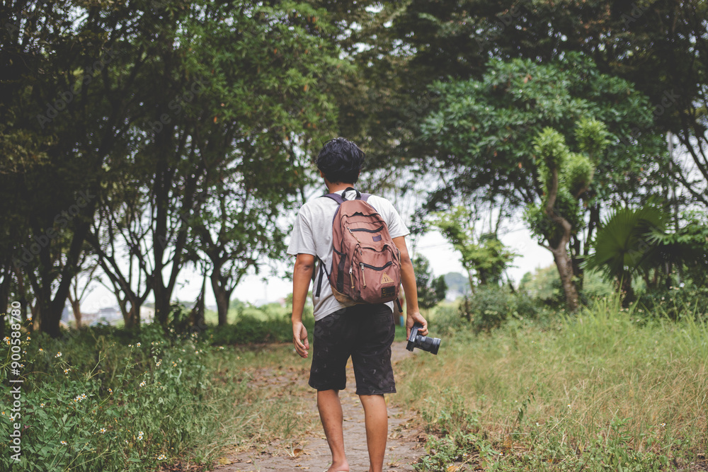 Solo backpacker with camera in hand walks alone. Back view photo of ...