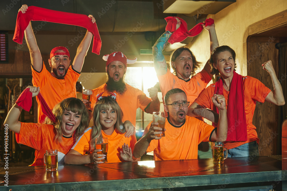 Excited fans, women and men, sitting at bar counter shouting, screaming ...