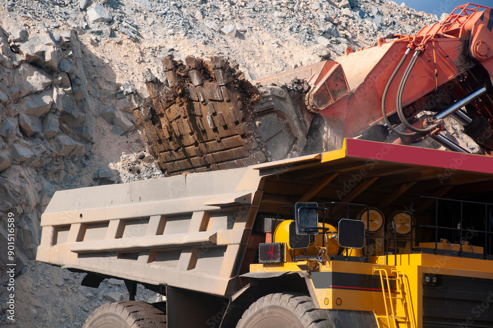 The photo shows a large excavator loading iron ore into a massive dump ...