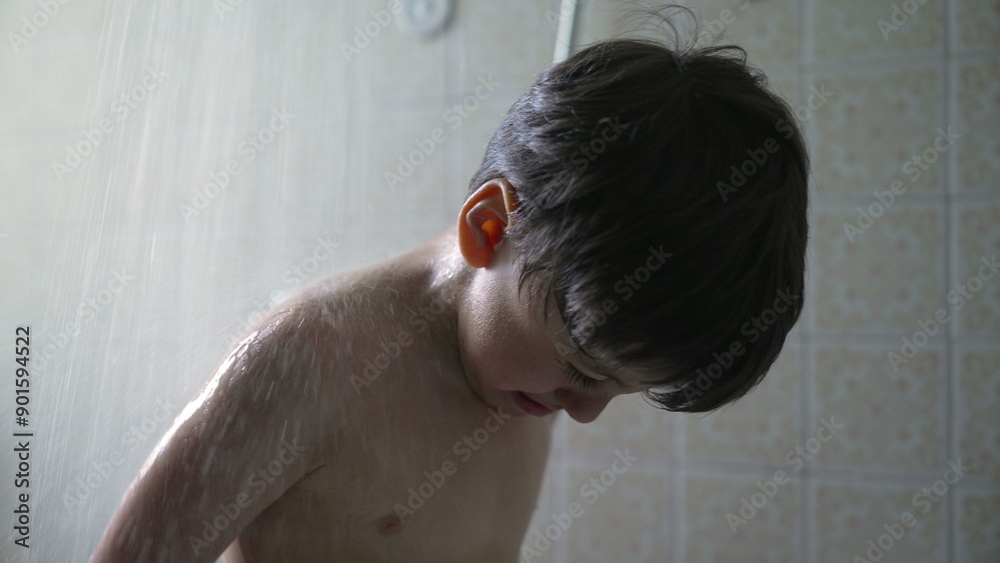 Young boy crying under shower water, close-up of a child in tears ...