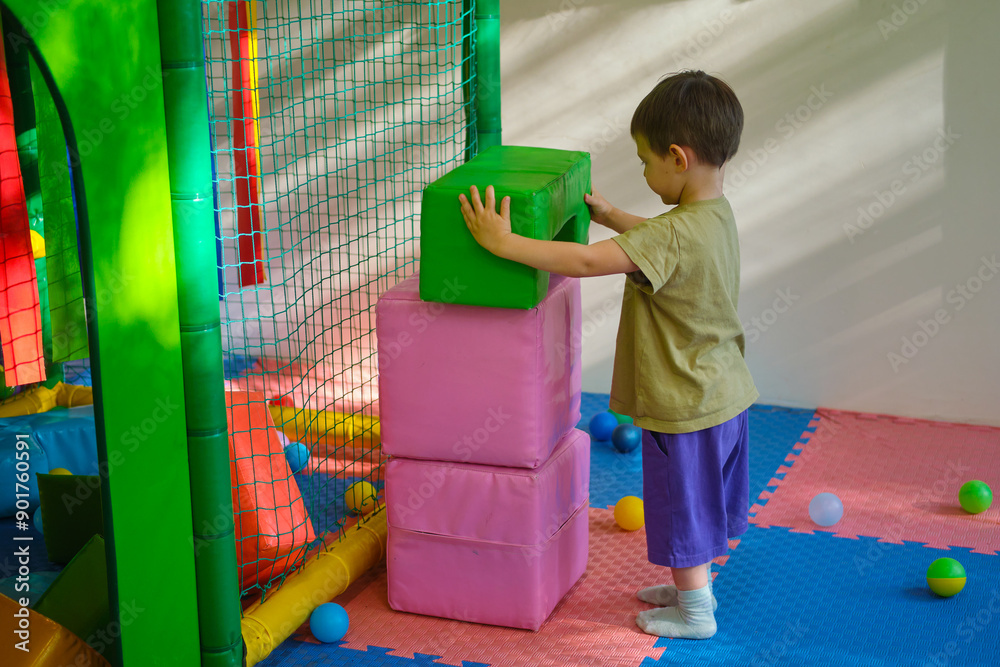 Child stacking soft blocks in indoor playground. Indoor playground ...