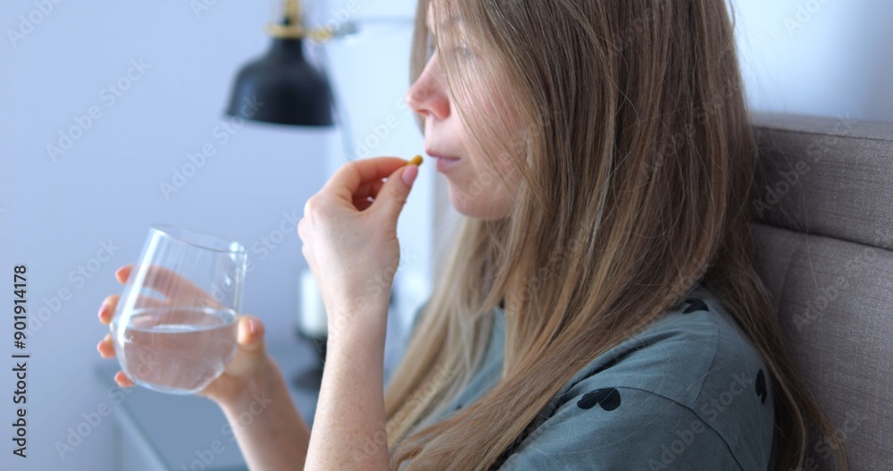 Haggard woman with disease takes medicine capsule with fresh water ...