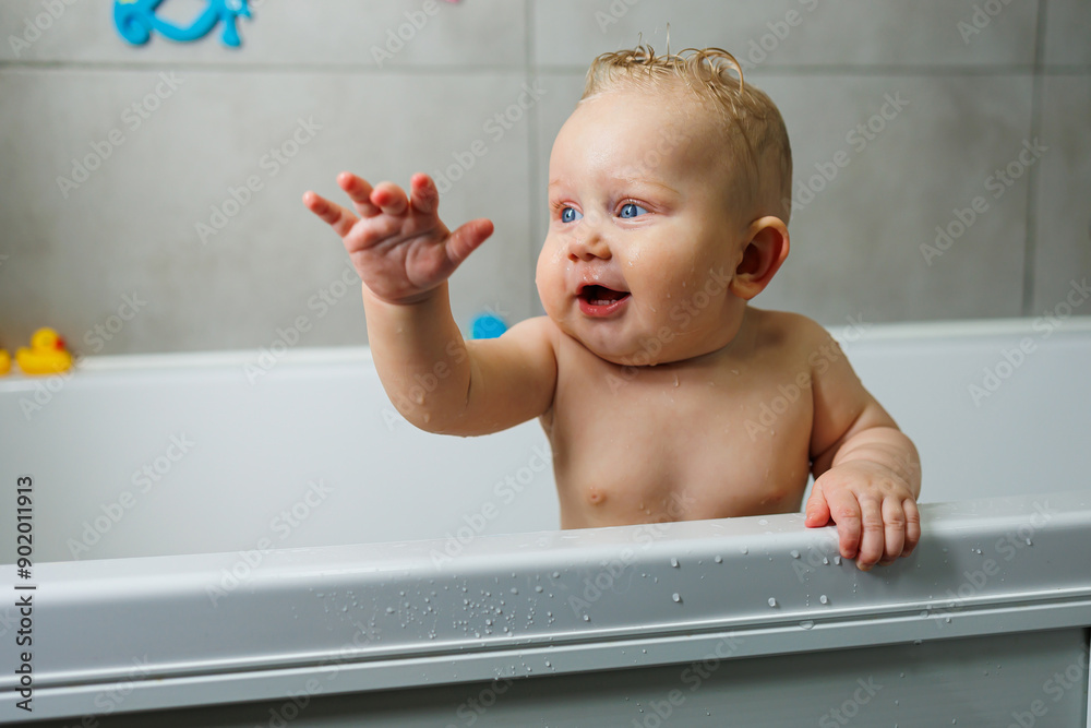 A blue-eyed baby with a bare torso is standing in the bathroom and ...