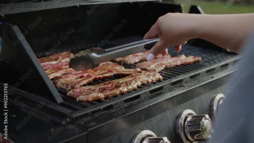 During the sunset, a woman grilled barbecue on a gas grill in the front ...