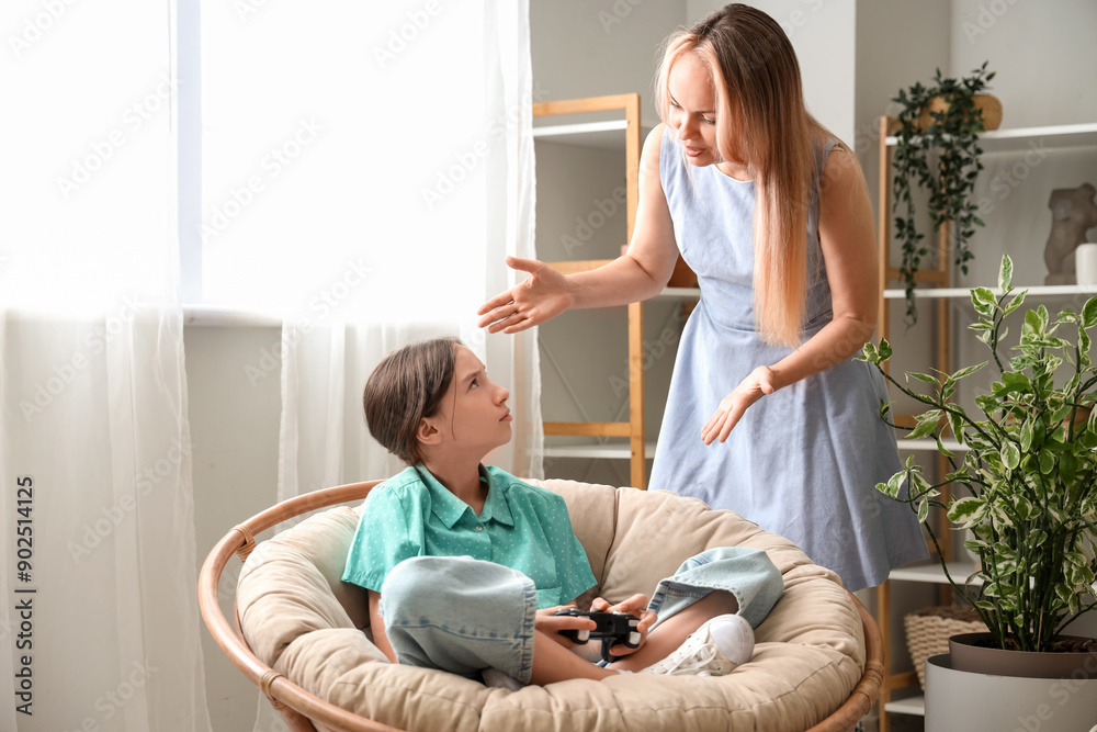 Mother arguing with her teenage daughter playing video game at home ...