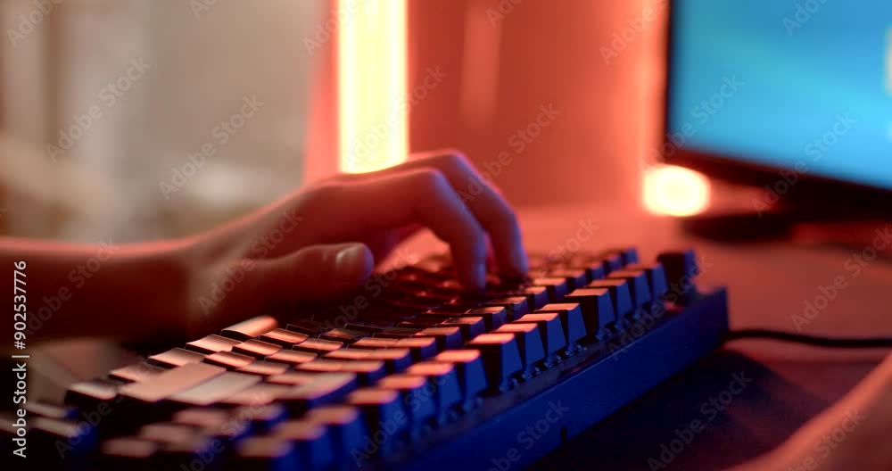 Illuminated by a red backlight, typing on a computer keyboard in a ...