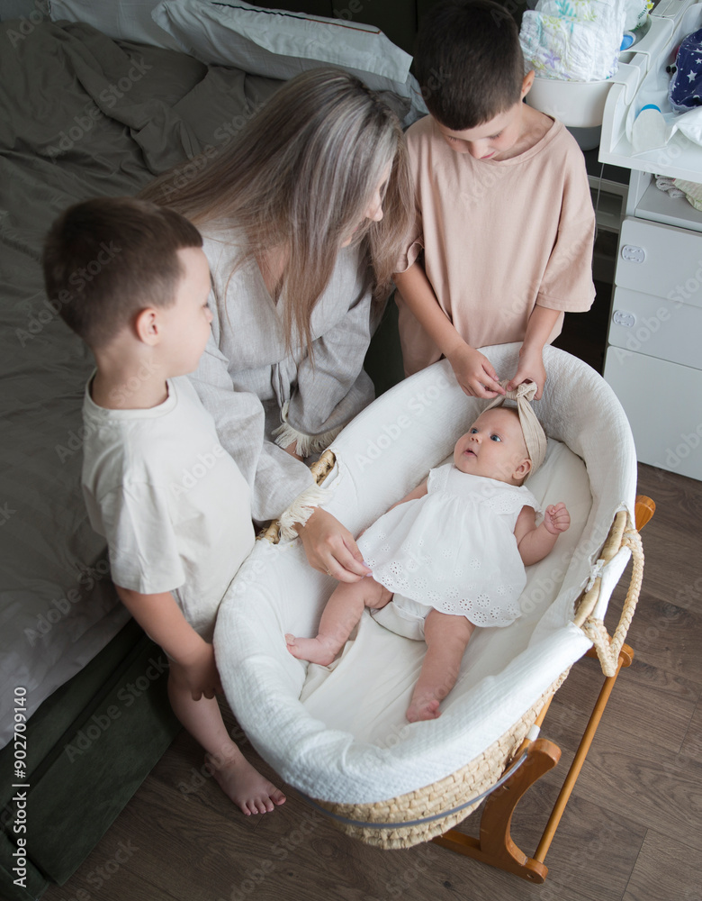 Mom and two kids standing at crib of newborn baby girl. Mother and ...