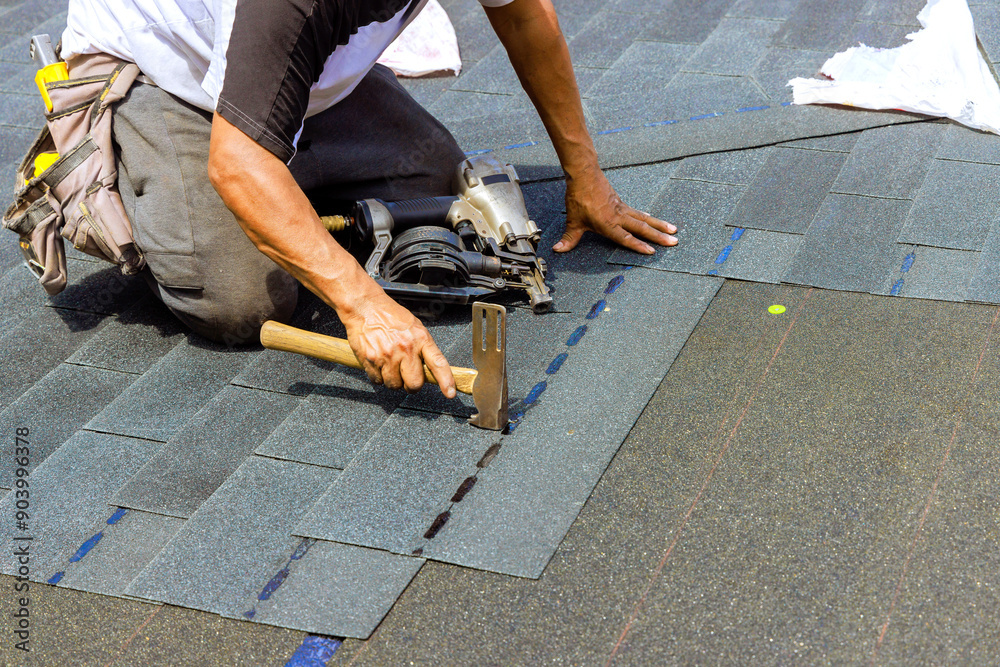 An installation worker using an air pneumatic nail gun installed new ...