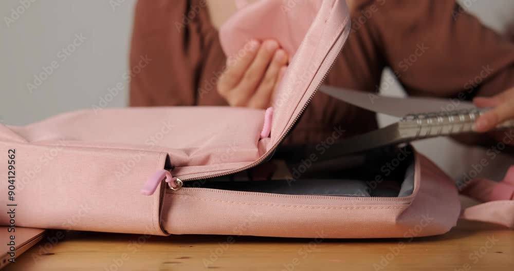 Close-up of a teenage girl hands as she packs her school backpack to go ...
