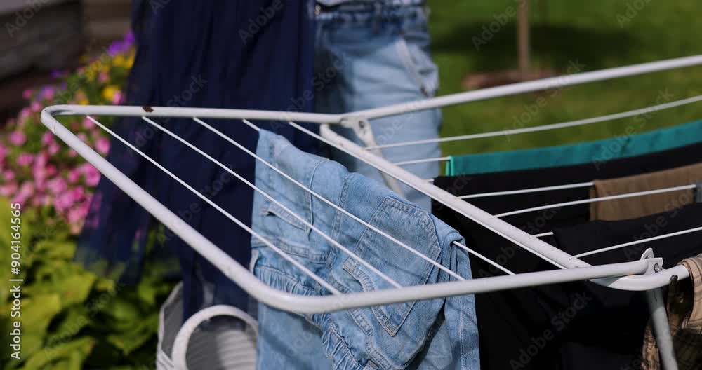 woman hang out the laundry outdoors on clothes airer rack at home ...