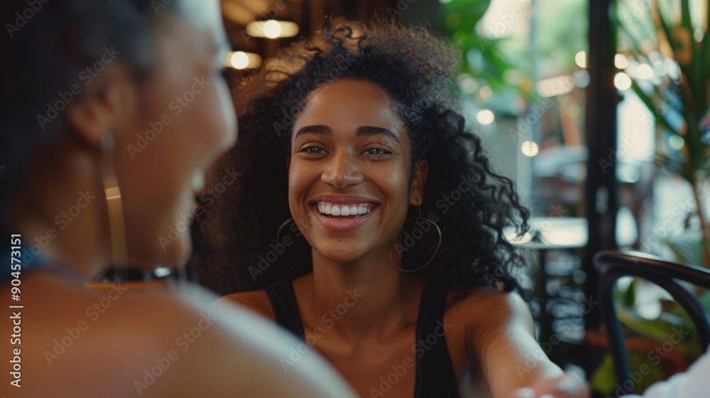 In a warm, cozy coffee setting, the young woman smiles and shakes hands ...