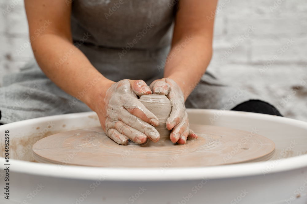 Placing the clay in the center of pottery wheel to start forming the ...