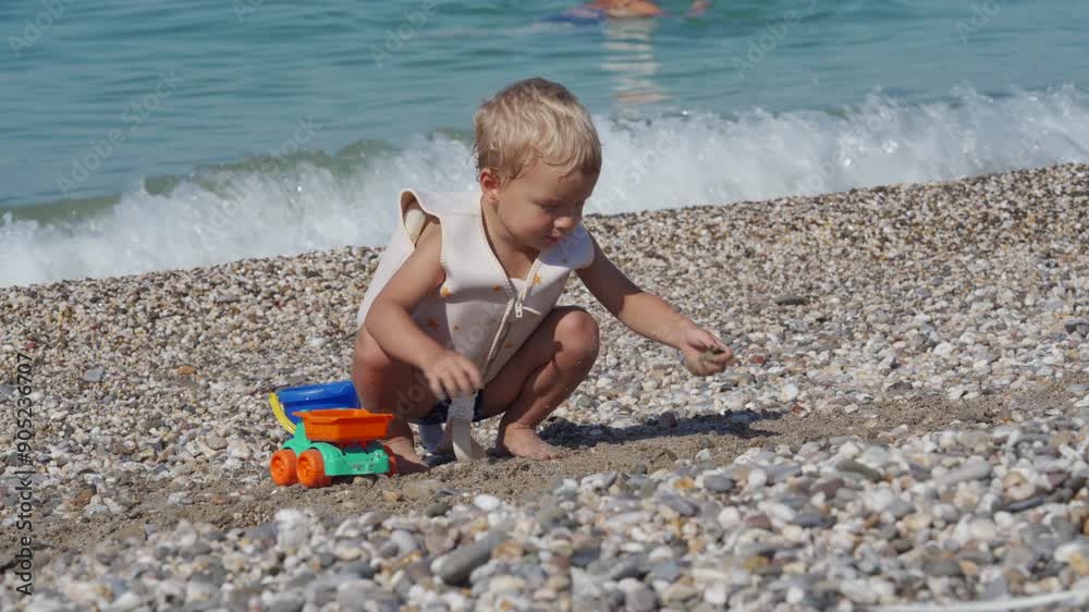 Happy little boy in swim vest life jacket playing on summer beach ...