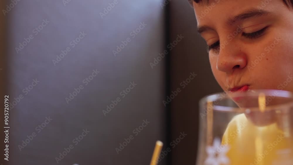 Boy eating crispy chicken burger with lettuce, pickles, and tomato in ...