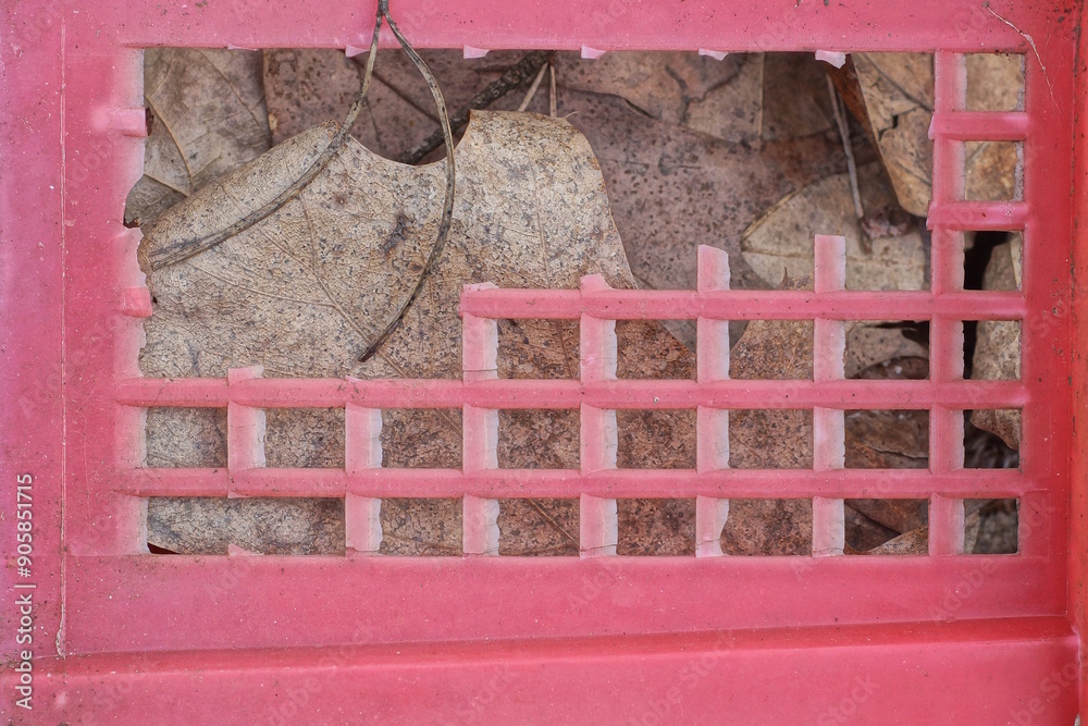 red plastic texture from a broken grate on the street on a brown ...