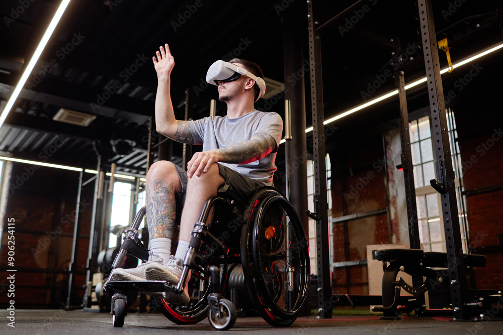 Side view portrait of young man with disability using wheelchair in gym ...